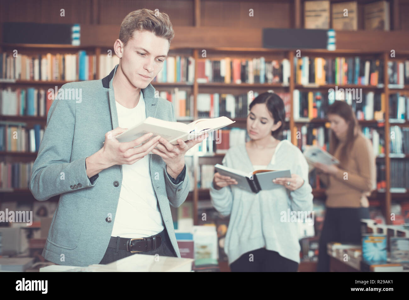 Young guy reading interesting books in bookshop Stock Photo - Alamy