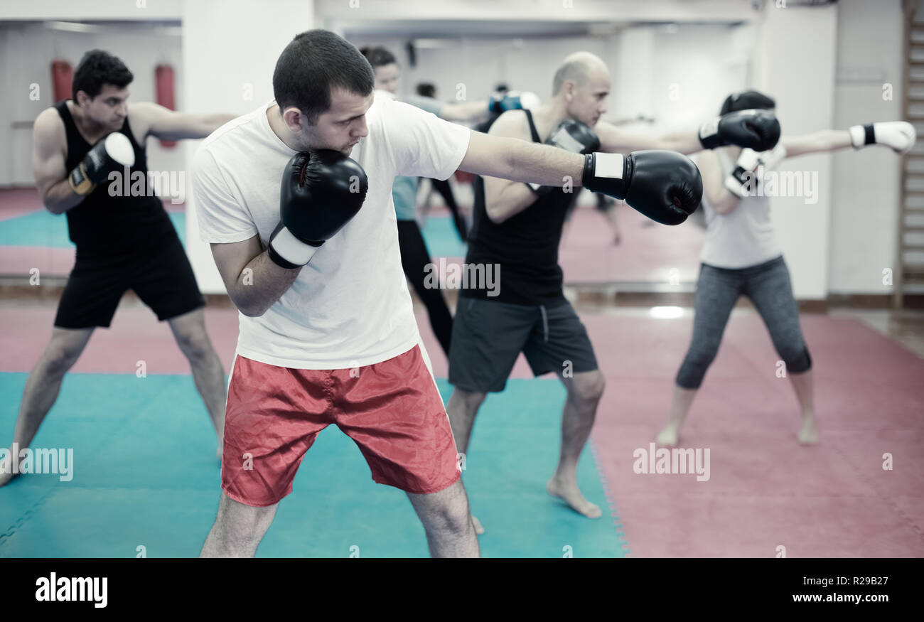 Group of athletic people of different ages training in the boxing hall ...