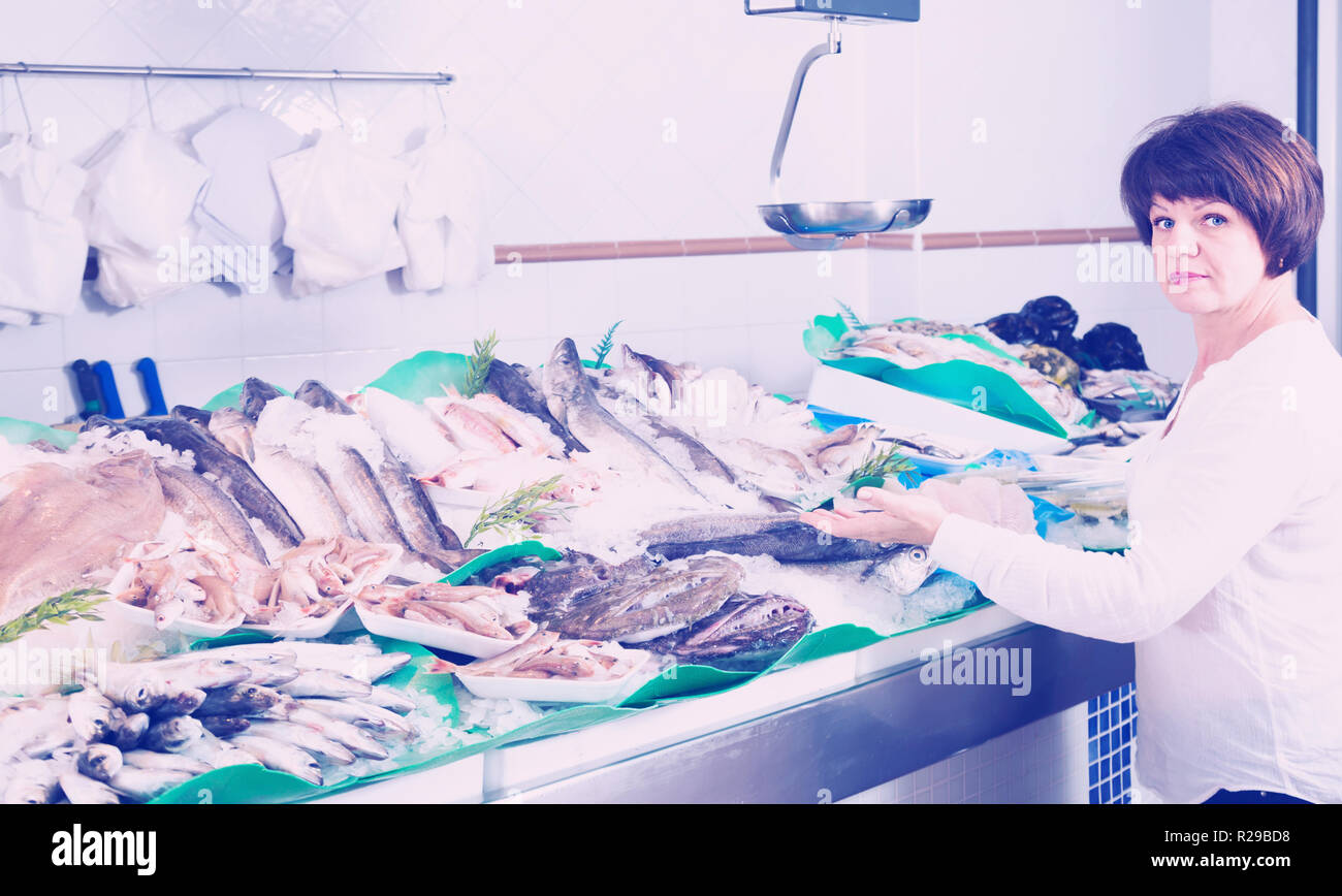 Adult female customer buying fish and chilled seafood in shop Stock ...