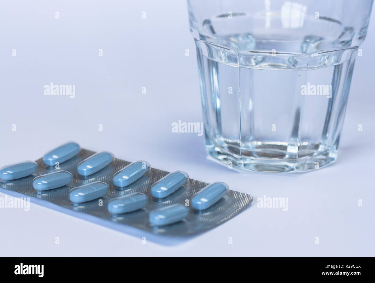 Glass of water and blue pills in blister. Vitamines. Antibiotics. Drugs ...