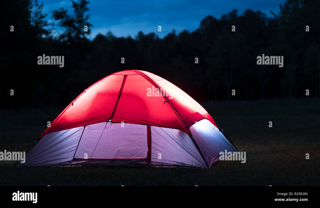 Lighted red and white nylon camping tent after the sun has set Stock ...