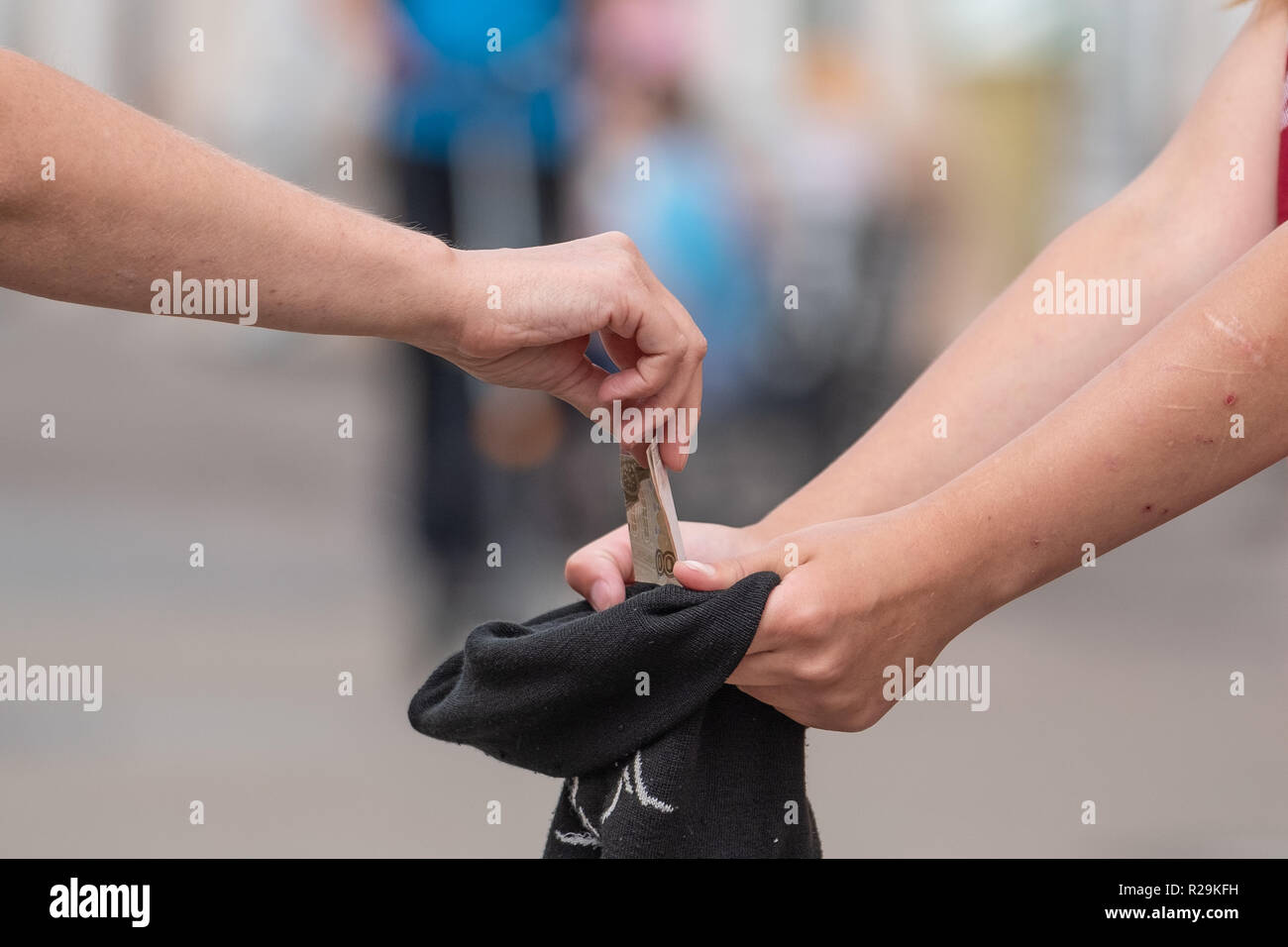 Photo of a female hand giving alms into the hat Stock Photo - Alamy