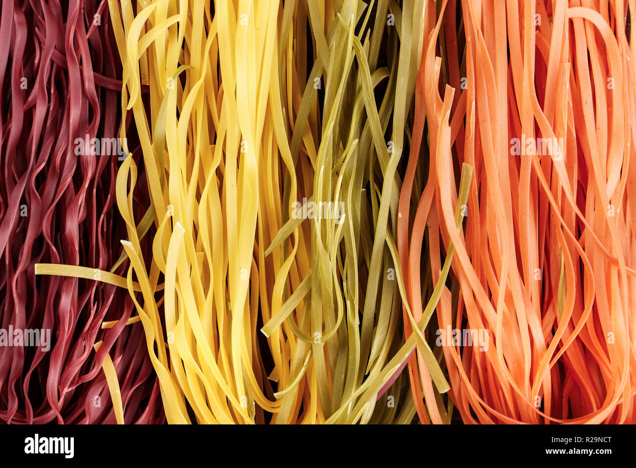 A lot of raw multi-colored pasta scattered as a background. space for ...