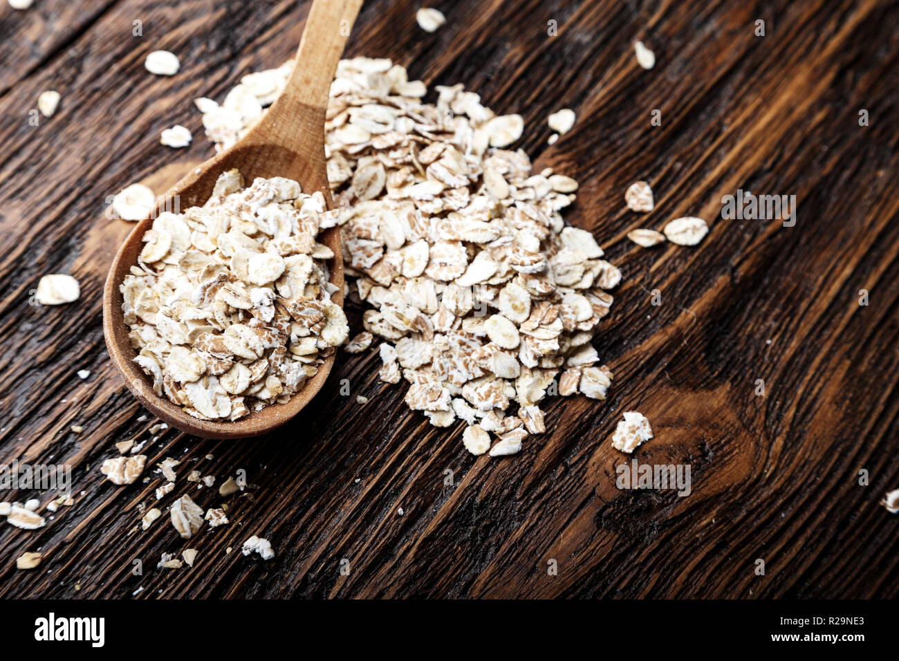 raw oatmeal flakes scattered on a wooden background. healthy ...