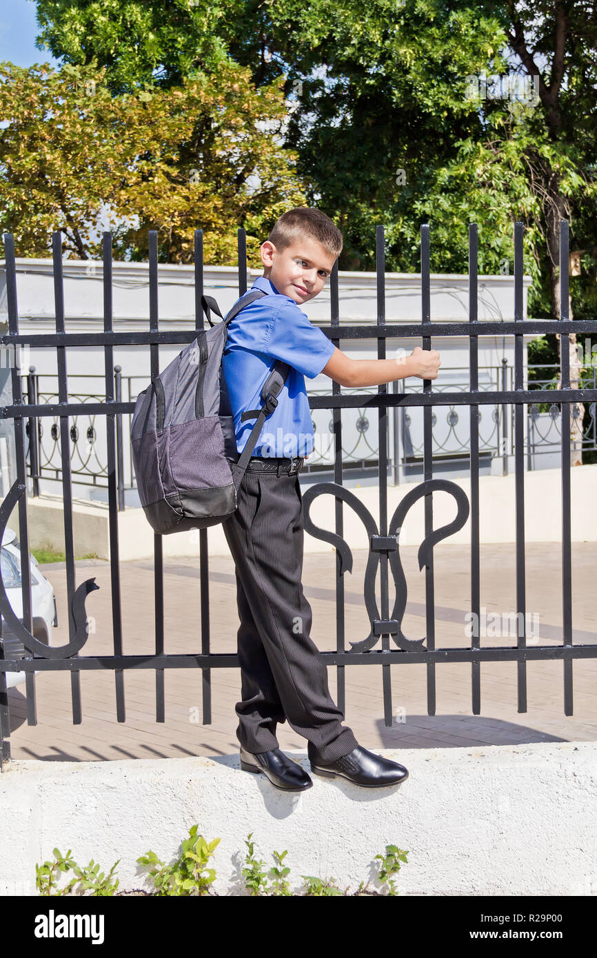 Cute boy are hanging on the fence with school backpack Stock Photo - Alamy