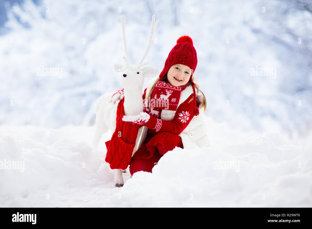 Child playing with reindeer in snow on Christmas vacation. Winter ...