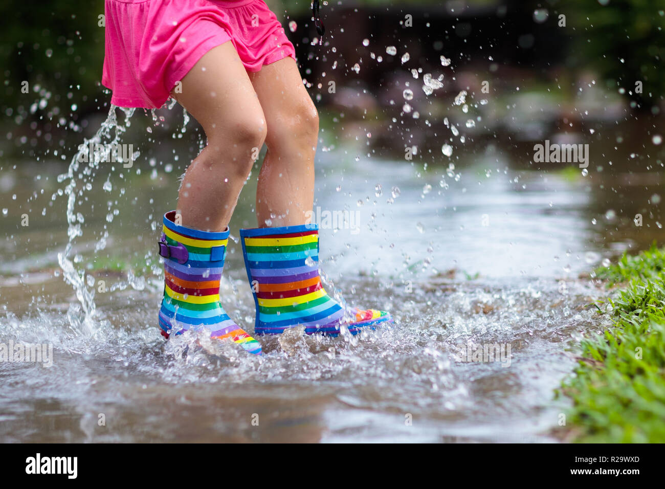 Kid playing out in the rain. Children with umbrella and rain boots play ...