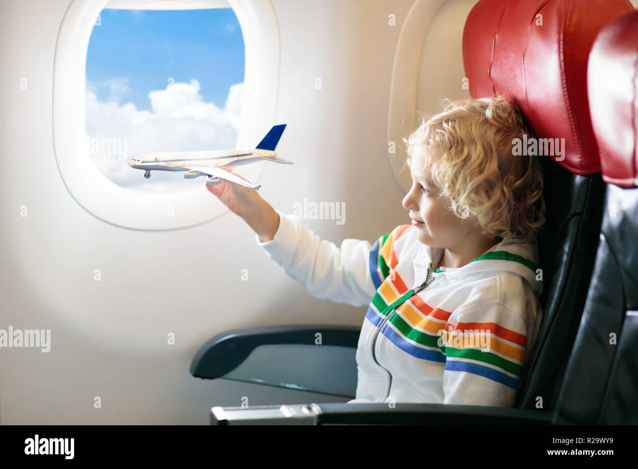 Child in airplane. Kid in air plane sitting in window seat. Flight ...
