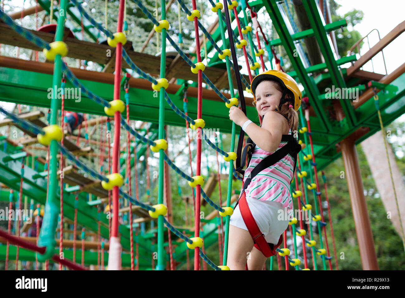 Child in forest adventure park. Kids climb on high rope trail. Agility ...