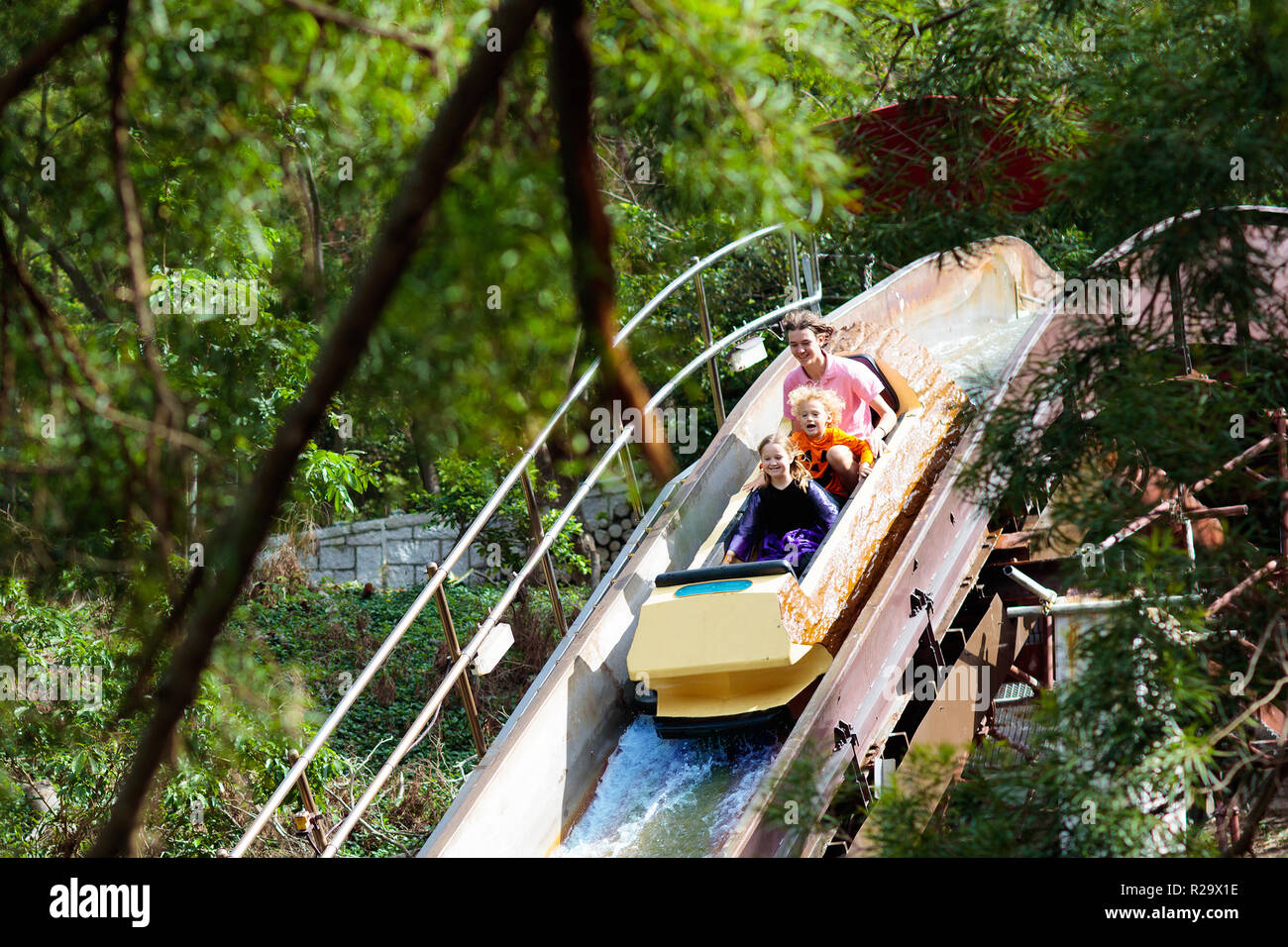 Family with kids on roller coaster in amusement theme park. Children ...