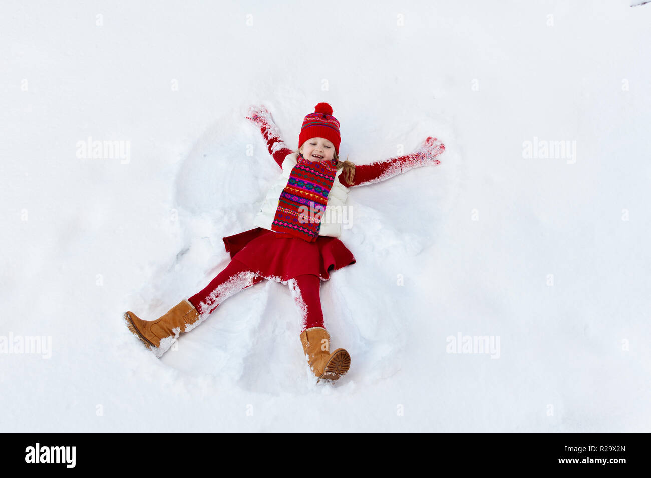 Child making snow angel on sunny winter morning. Kids winter outdoor ...