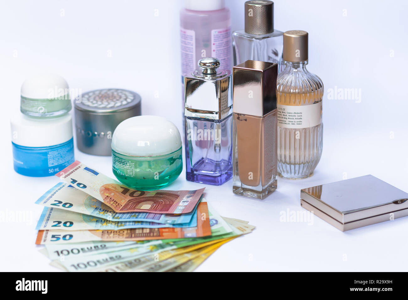 Banknote of euro and fragrance and cosmetics set on white background ...