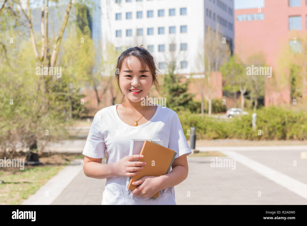 Female university college student holding books with campus background ...