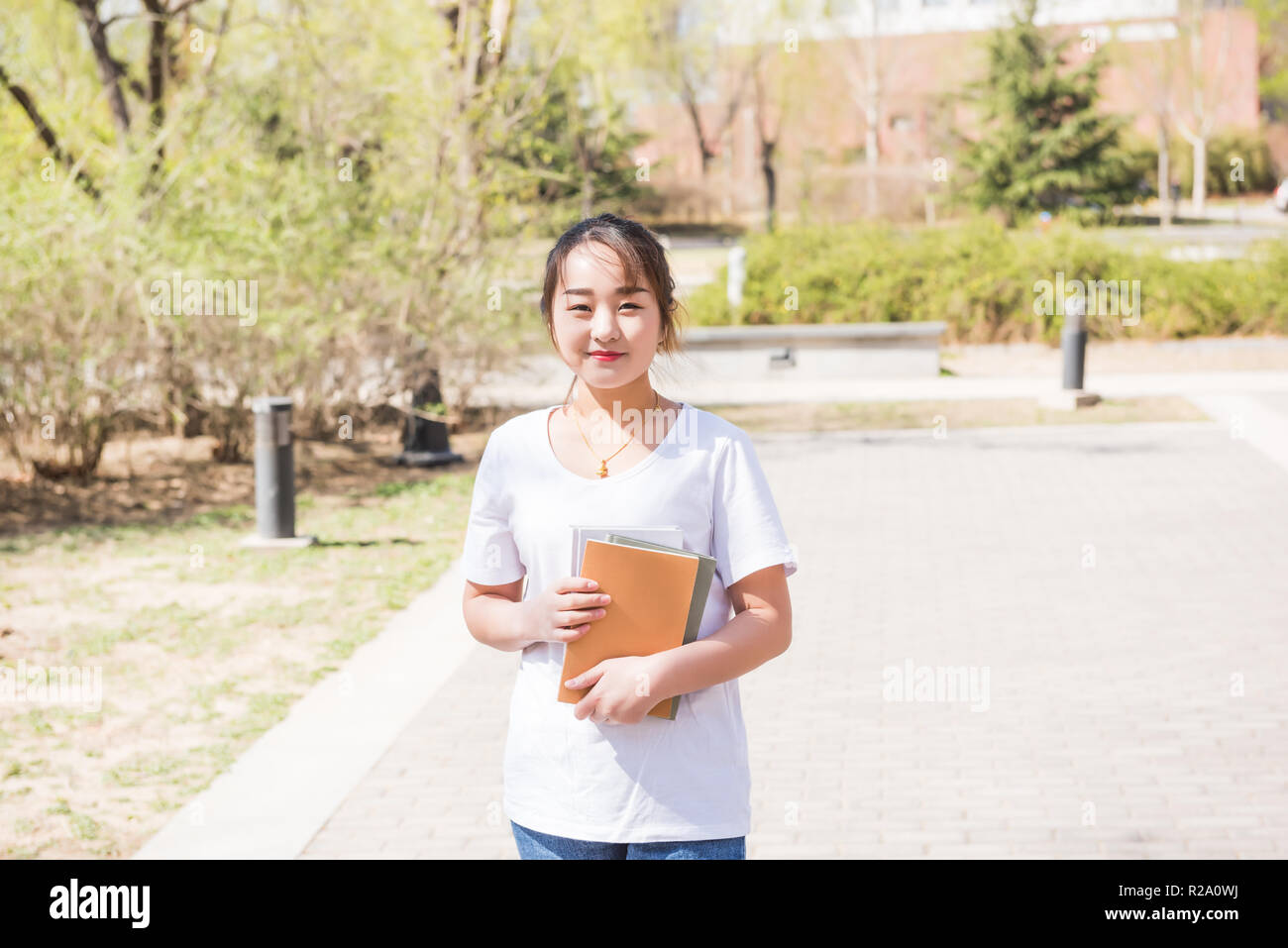 Female university college student holding books with campus background ...