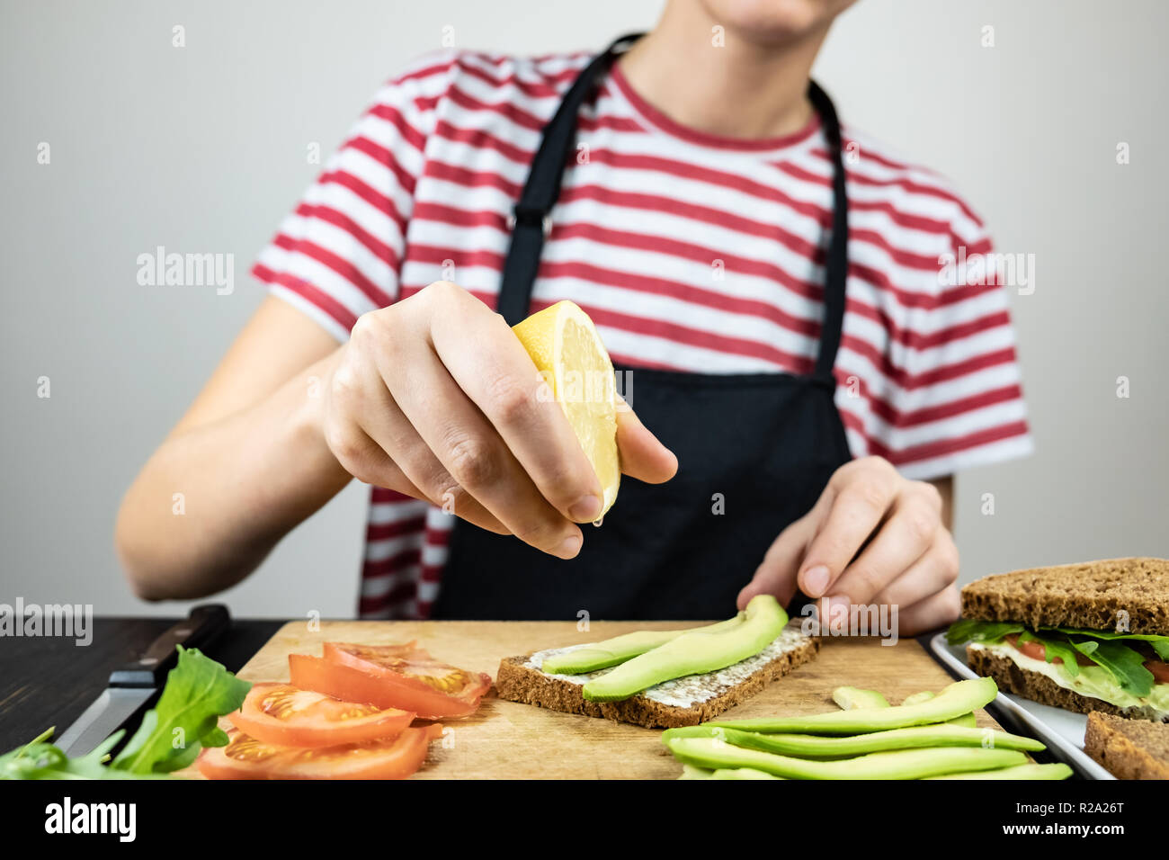 Making raw food snack. Female hands squeeze lemon juice onto avocado ...