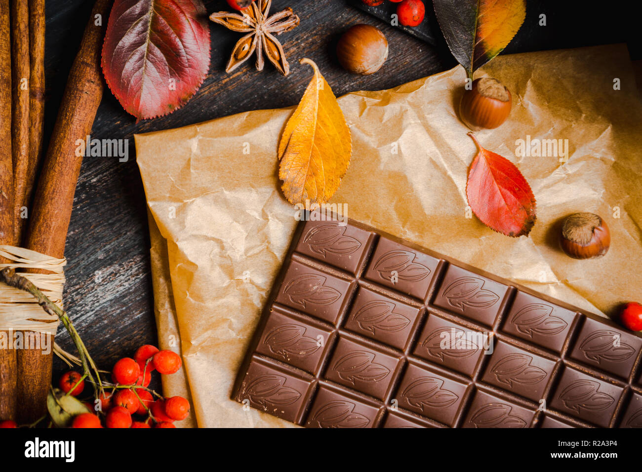 Chocolate bar with spices and autumn decoration on the rustic wooden ...