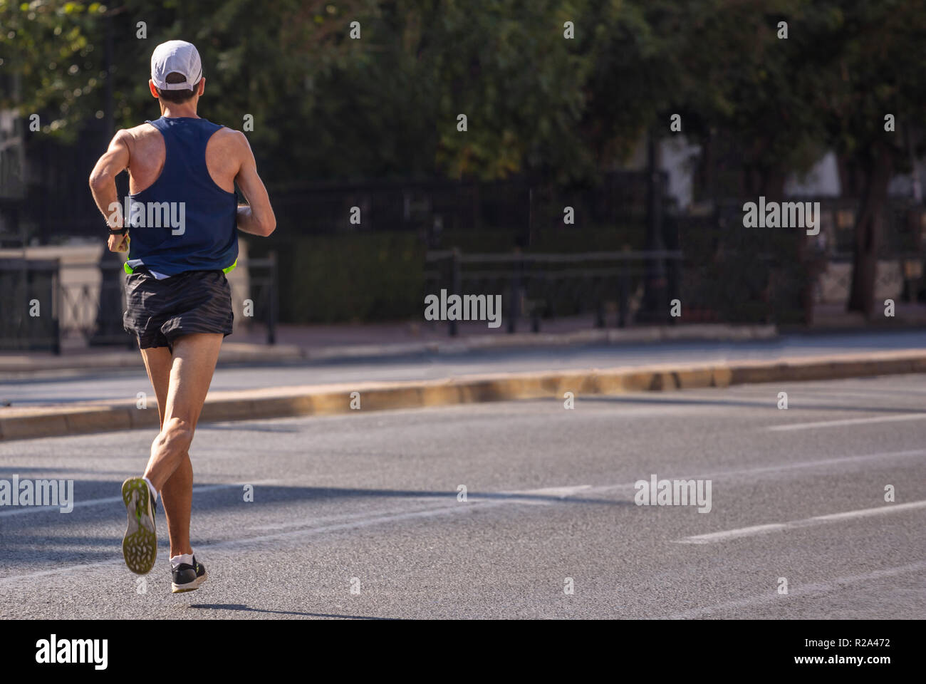 Running in the city roads. Young man runner, back view, blur background ...