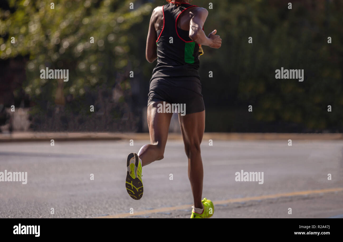 Running in the city roads. Young woman runner, back view, blur ...