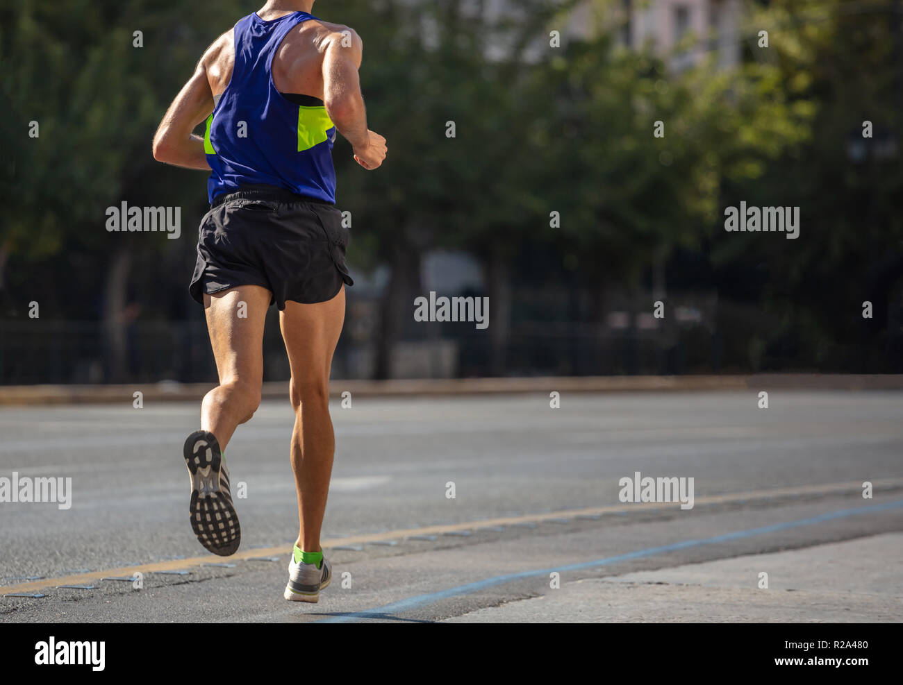 Running in the city roads. Young man runner, back view, blur background ...