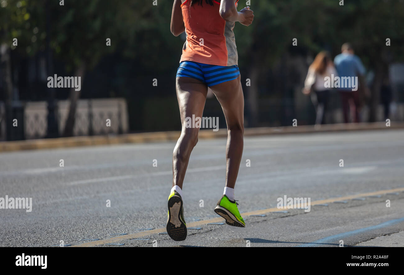Running in the city roads. Young woman runner, back view, blur ...