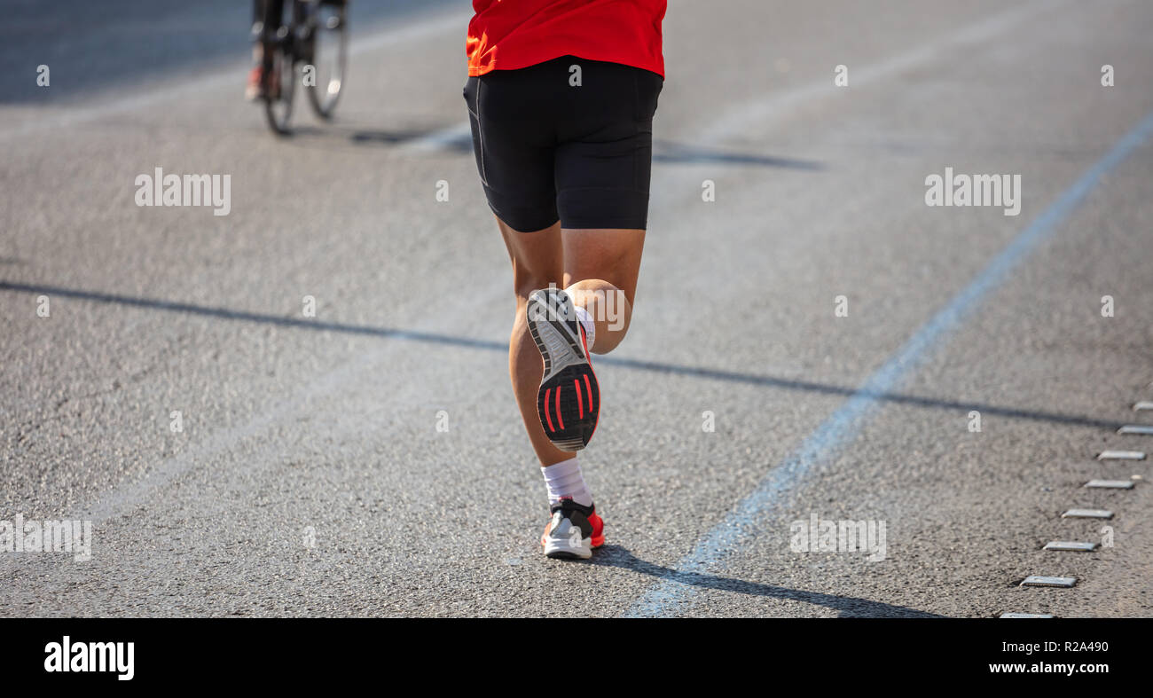 Running in the city roads. Young man runner, back view, blur background ...