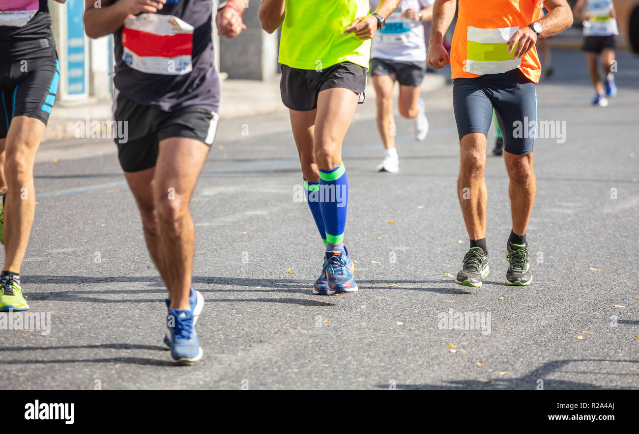 Marathon running race, group of runners on city roads, detail on legs ...