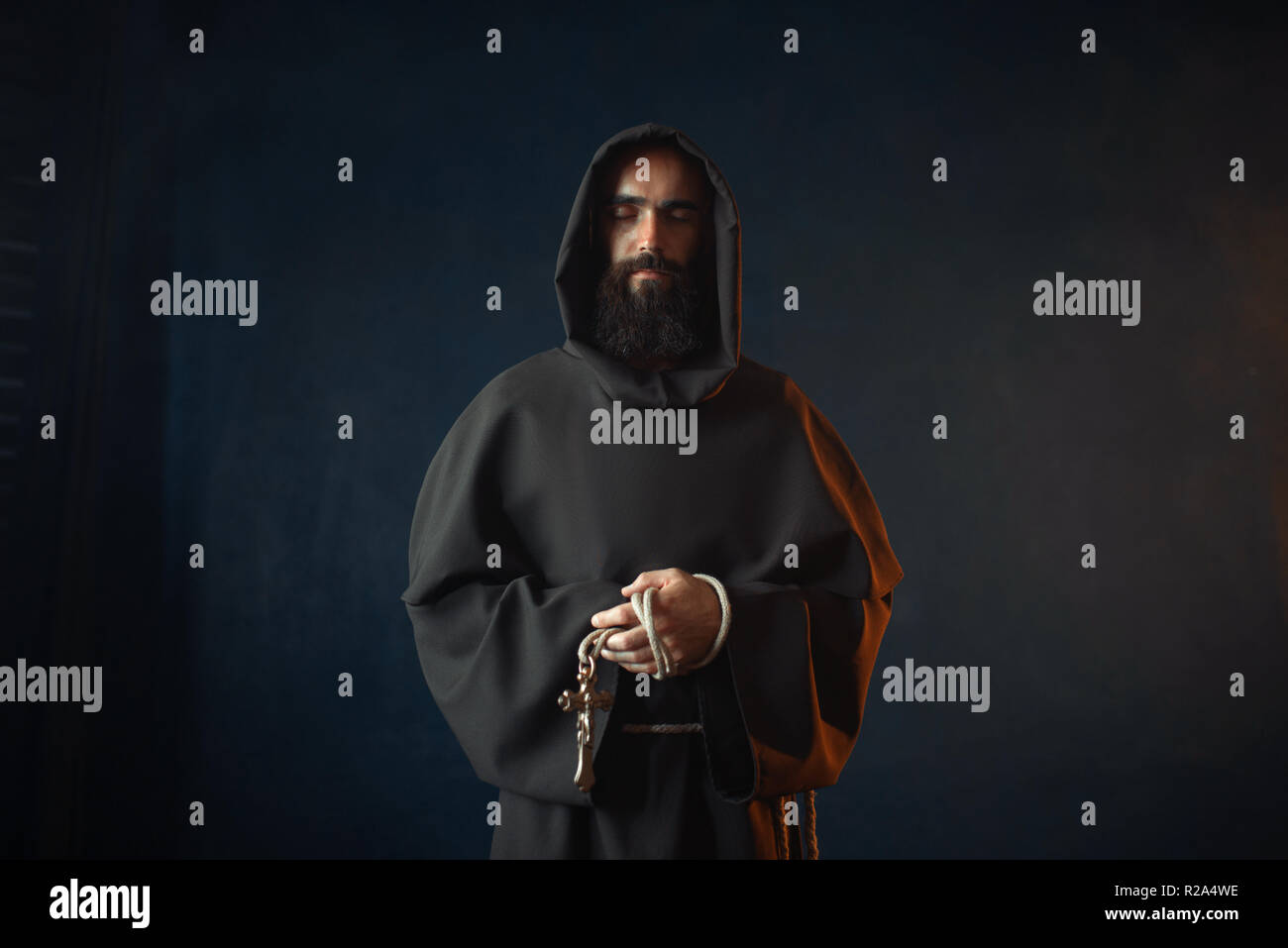 Medieval monk holds wooden cross in hands and praying, religion ...
