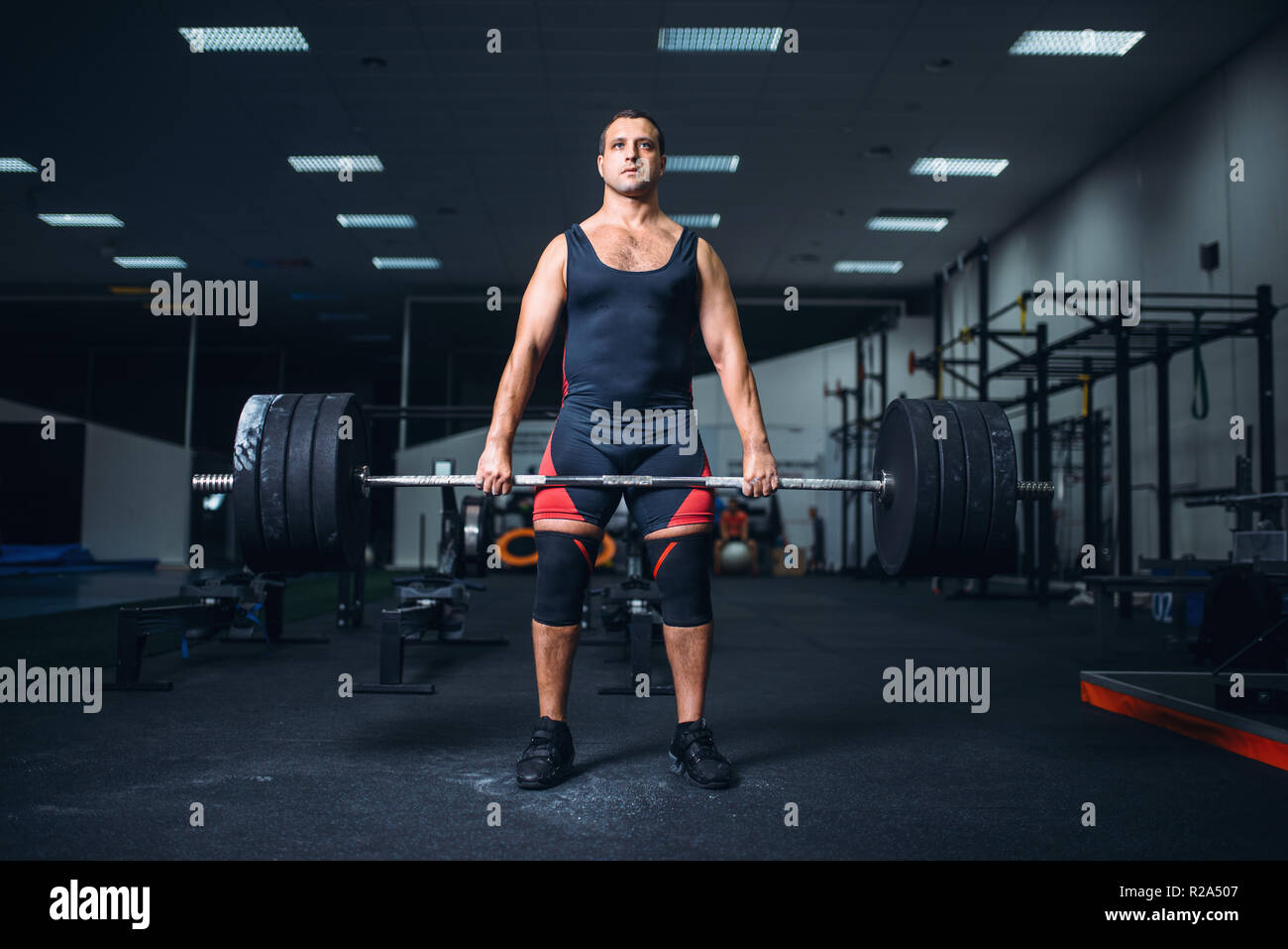 Strong male powerlifter keeps the weight of heavy barbell in gym ...