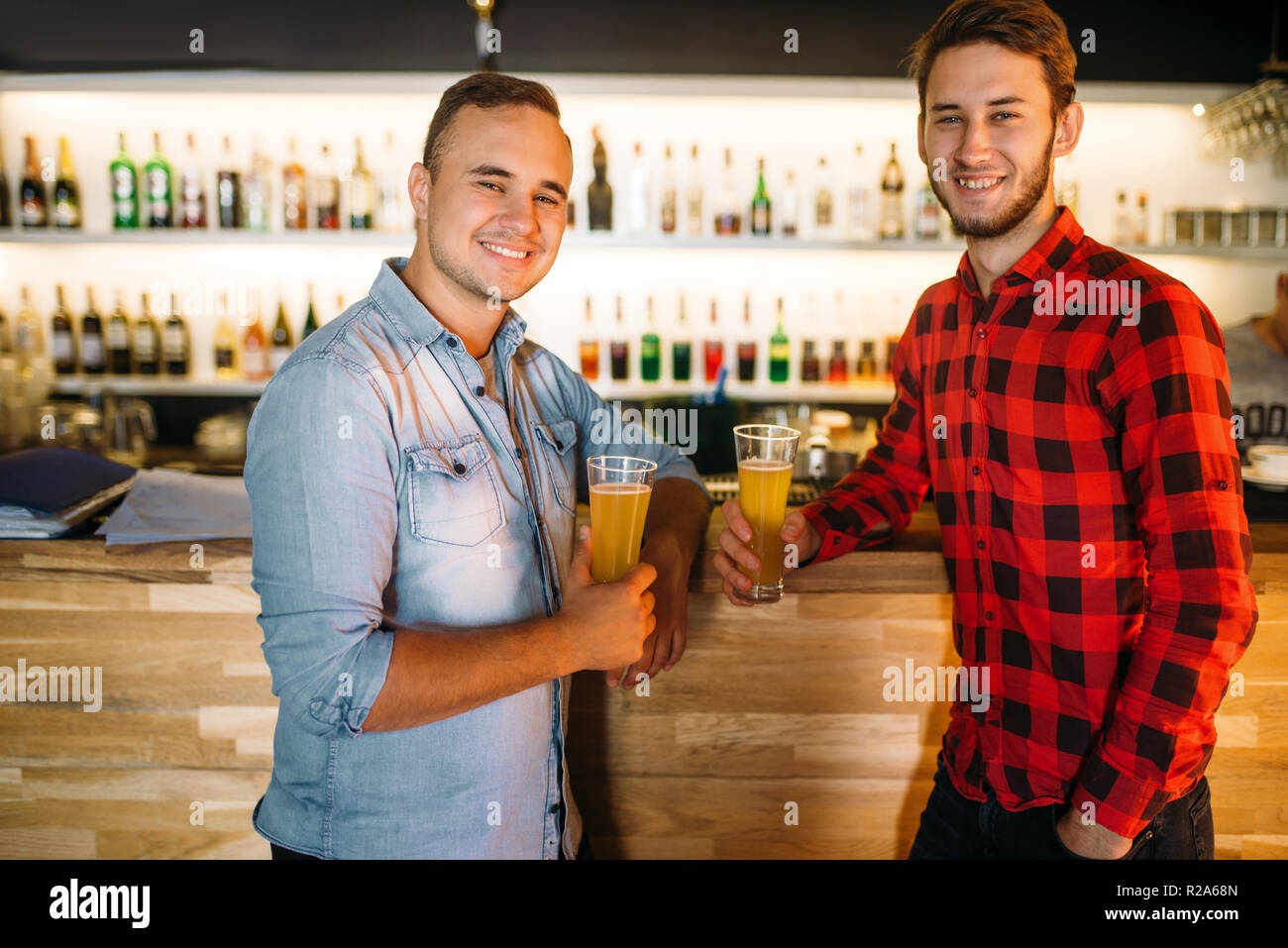 Two male bowlers drinks fresh juice at the bowling club bar counter ...