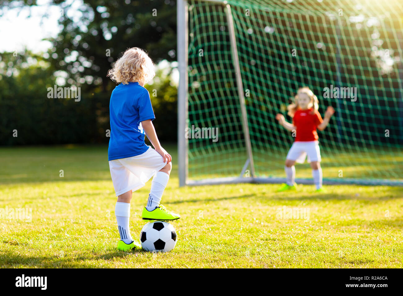 Kids play football on outdoor field. Children score a goal during ...