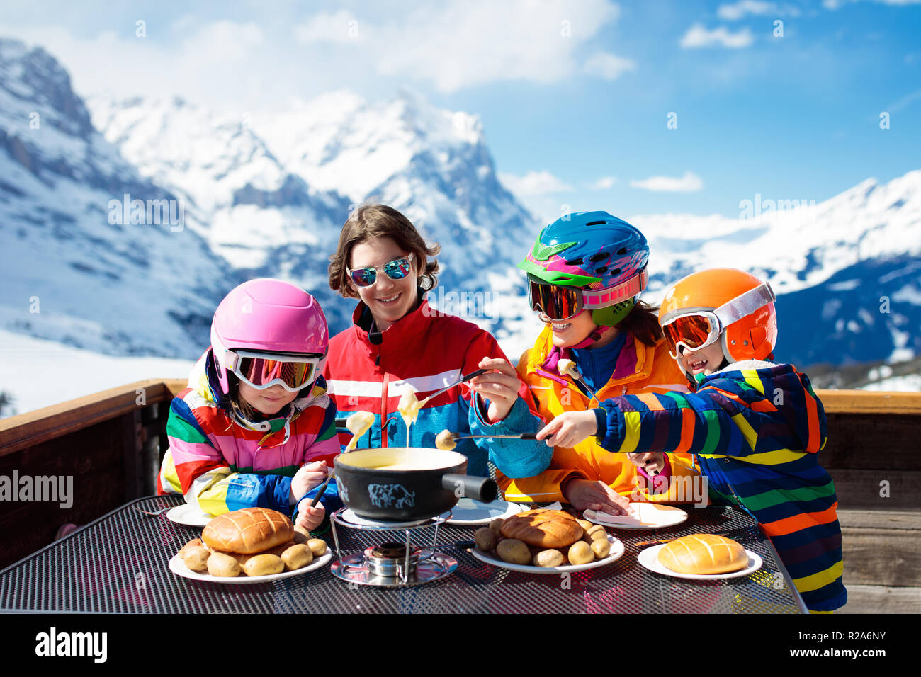 Family with children enjoying apres ski lunch with traditional Swiss ...