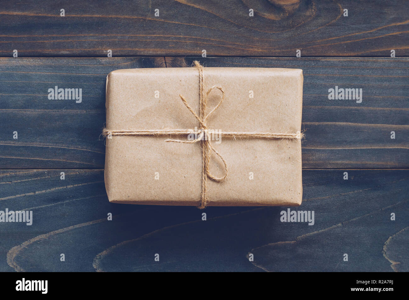 String or twine tied in a bow on kraft paper gift box no wooden table ...