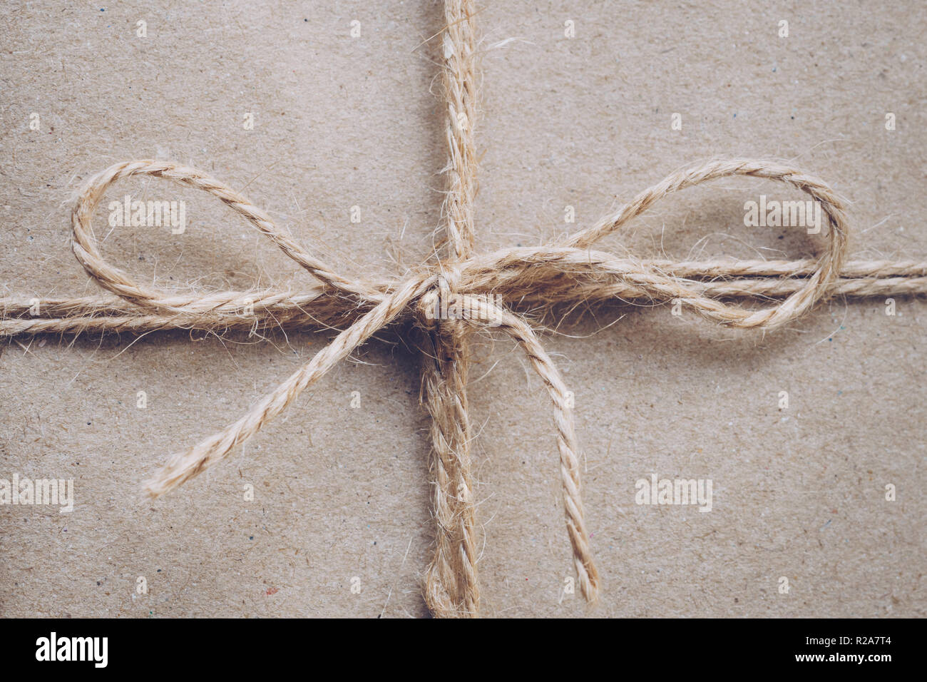 String or twine tied in a bow on kraft paper texture Stock Photo - Alamy