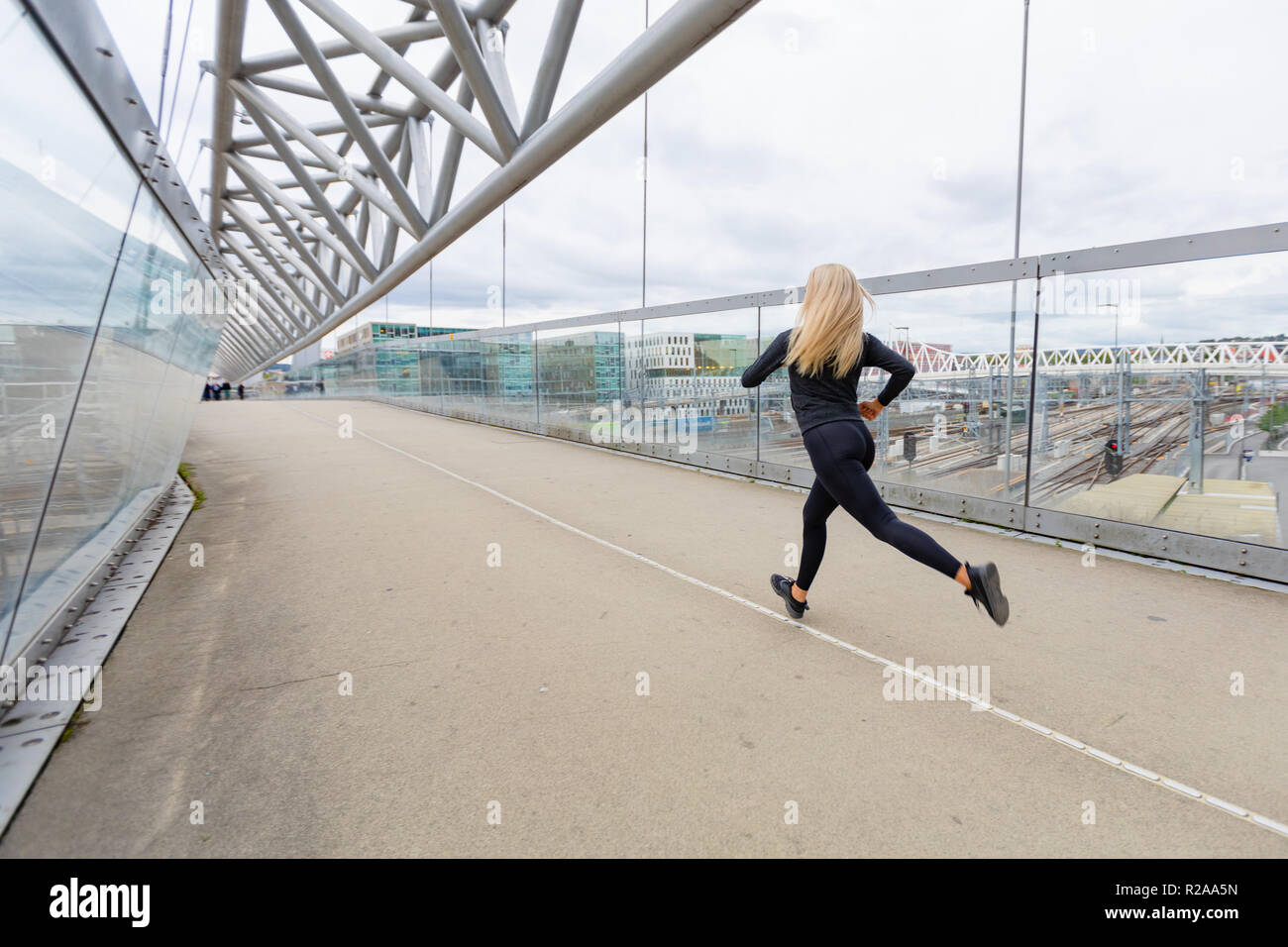 Female runner during fast running exercise in modern city at cloudy day ...