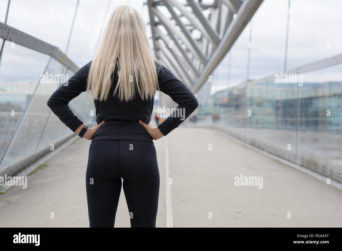 Fit blonde woman runner standing on bridge in modern looking city Stock ...