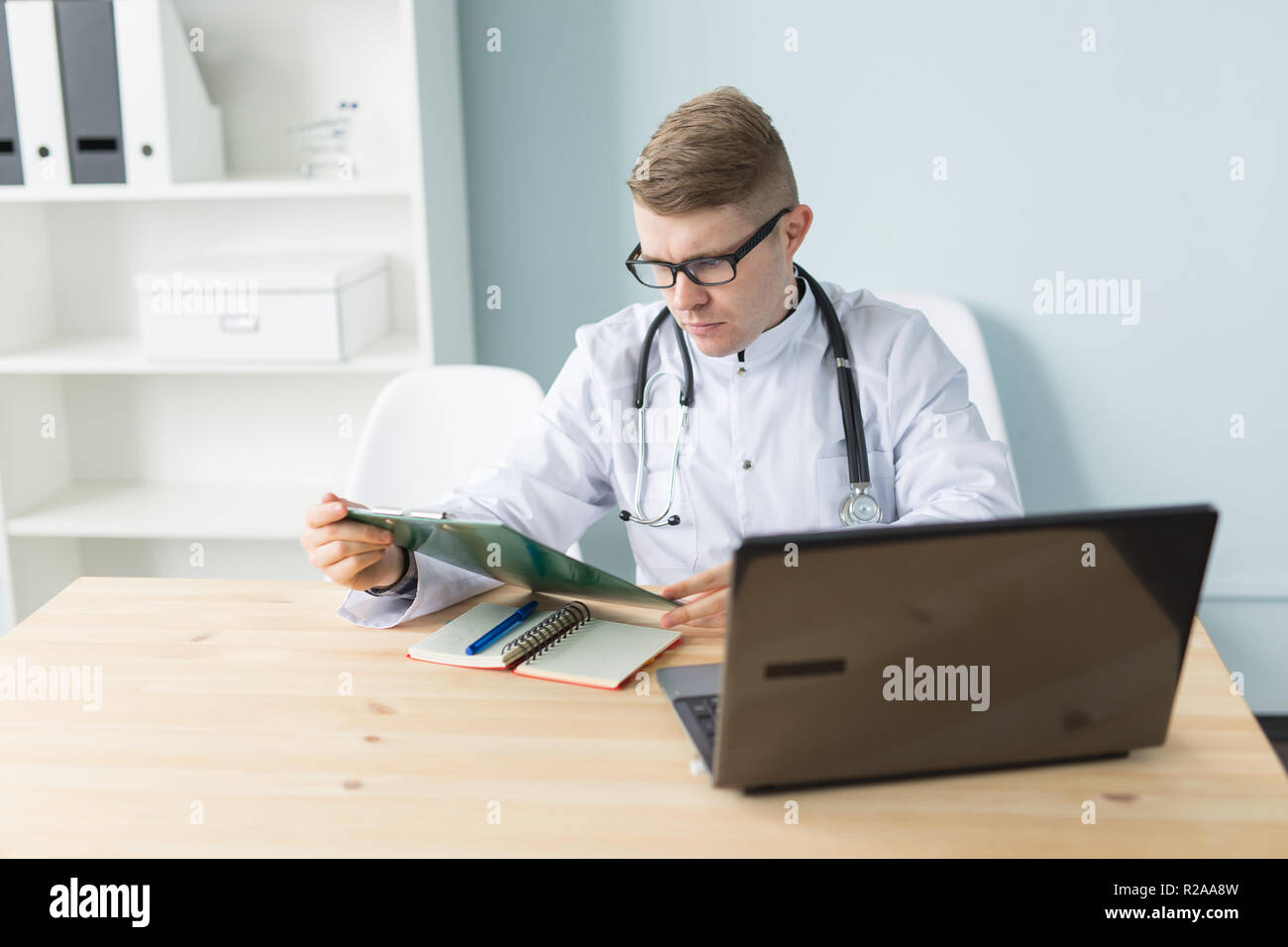 Medicine, working and people concept - handsome doctor sitting at the ...