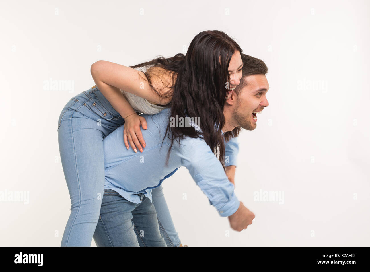 Couple posing on white background - funny man holding woman on his back ...