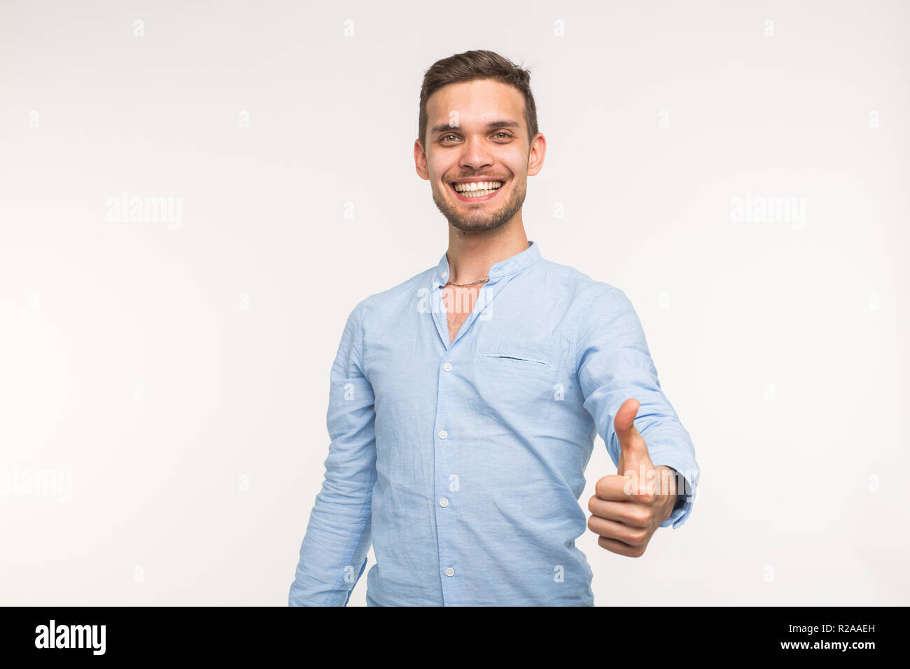 Portrait of stylish handsome young man with thumbs up isolated on white ...