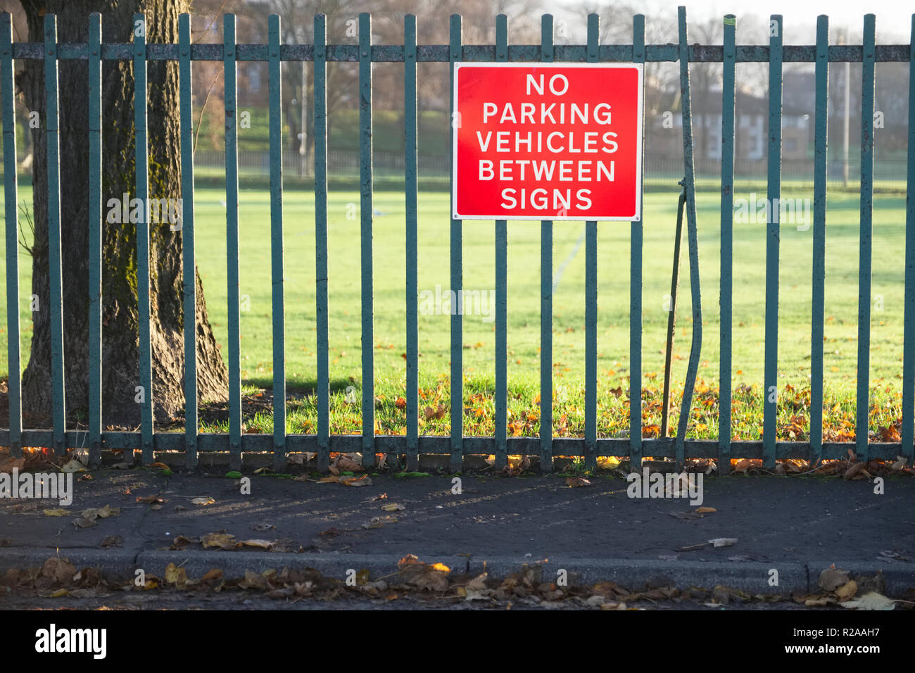 No parking between signs red sign on fence at park road Stock Photo - Alamy