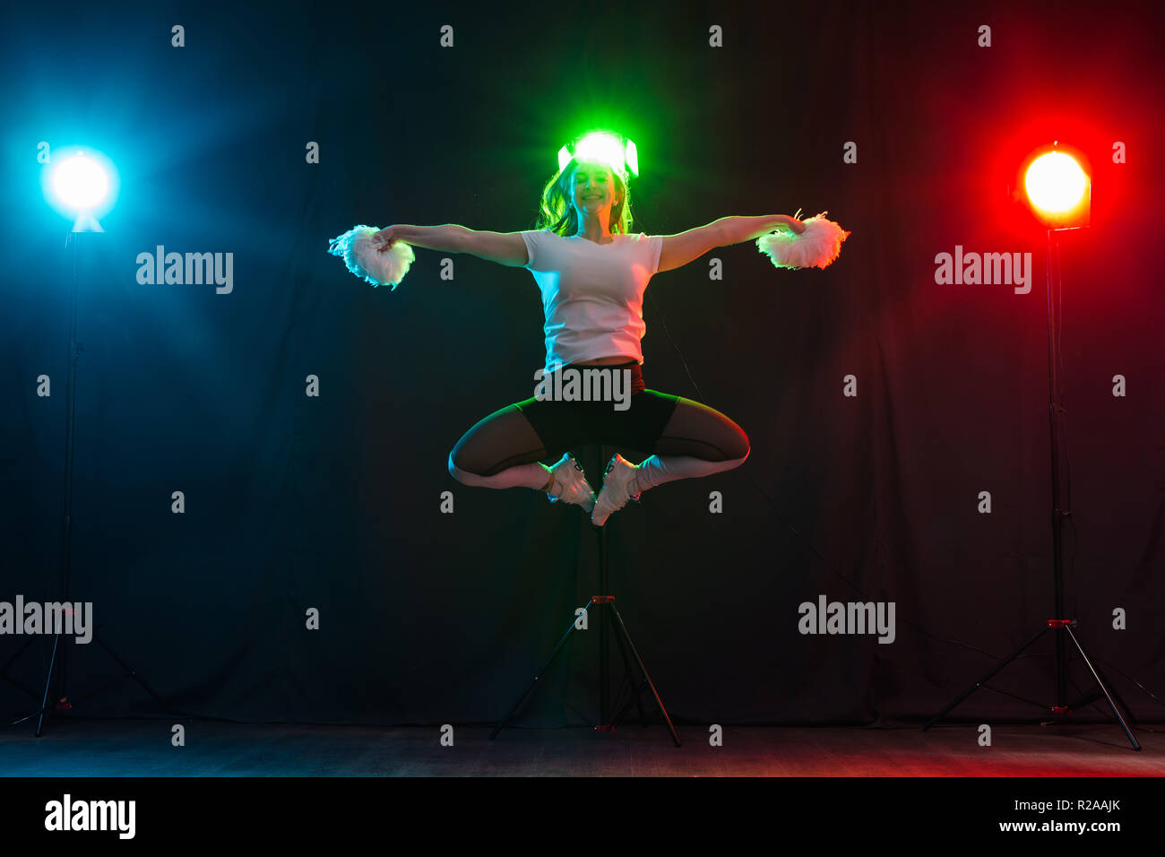 Cheerleading young woman dancing with pom-poms on colourful background ...