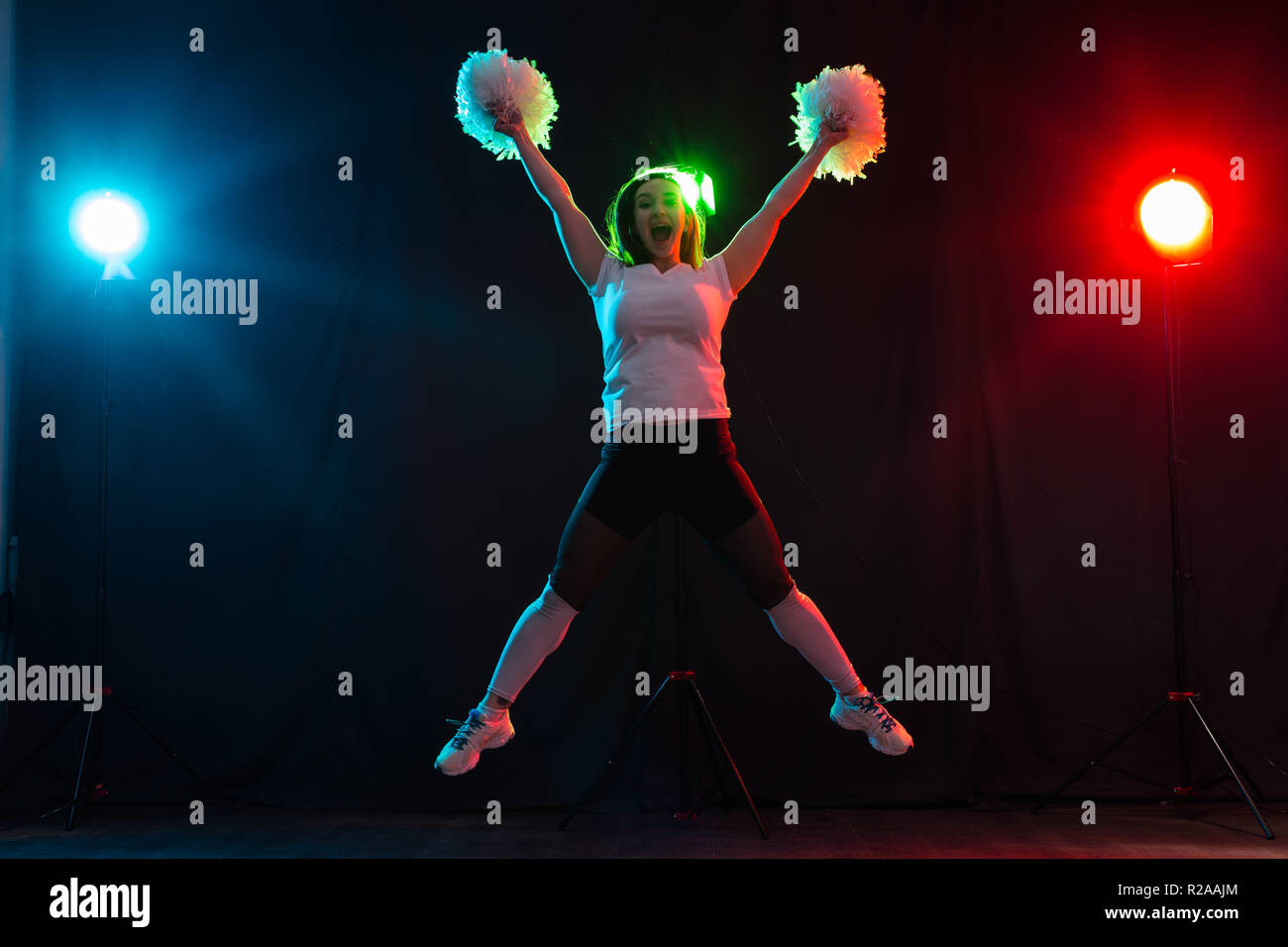 Cheerleading happy girl dancing on dark background Stock Photo - Alamy