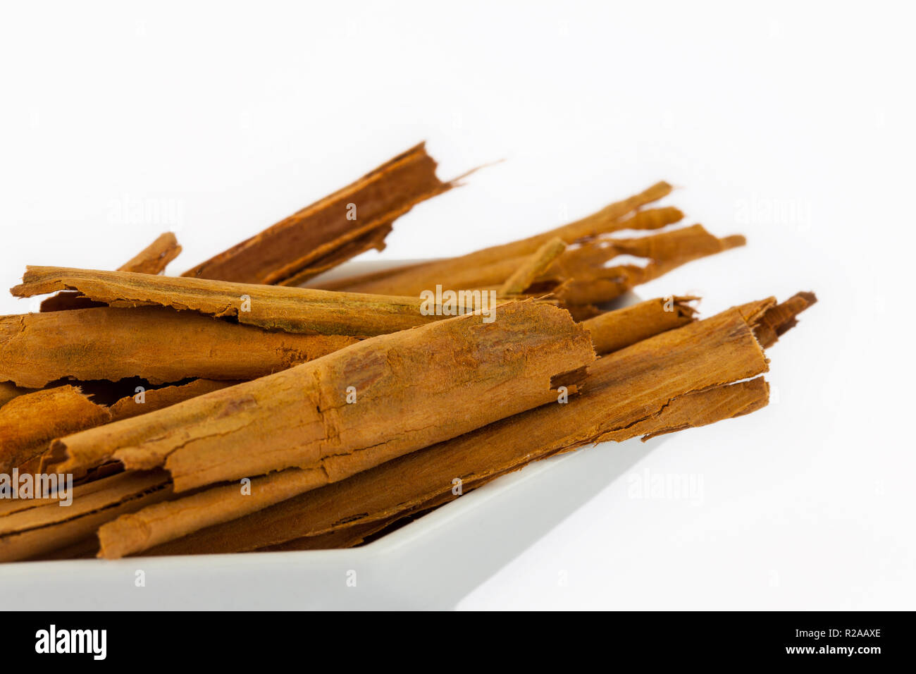 Dry cinnamon sticks in a small white ceramic dish isolated on white ...