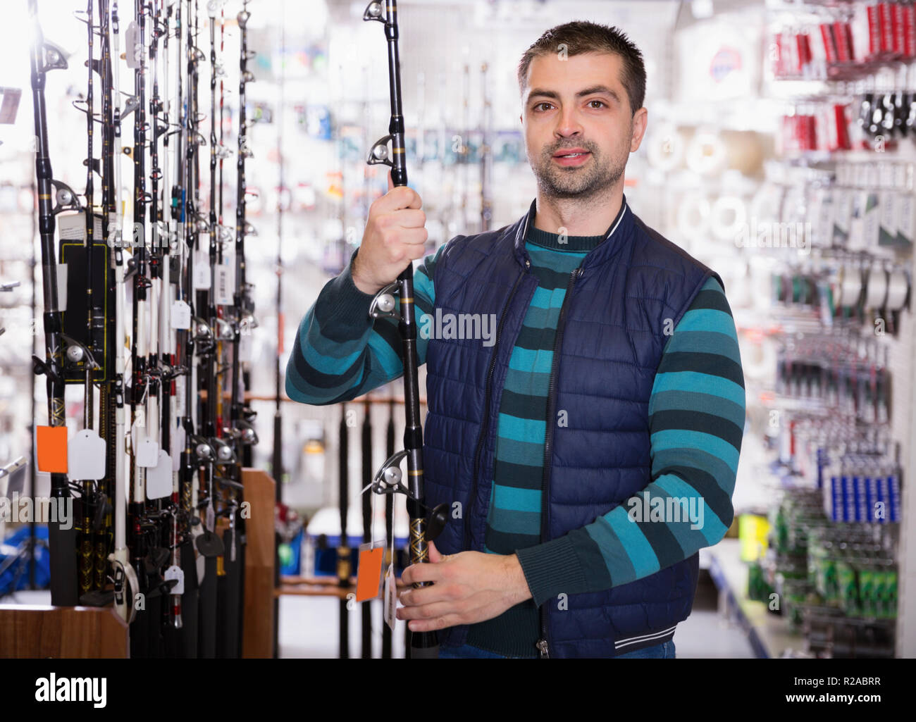 Fisherman consumer standing with fishing rod in the fishing shop Stock ...