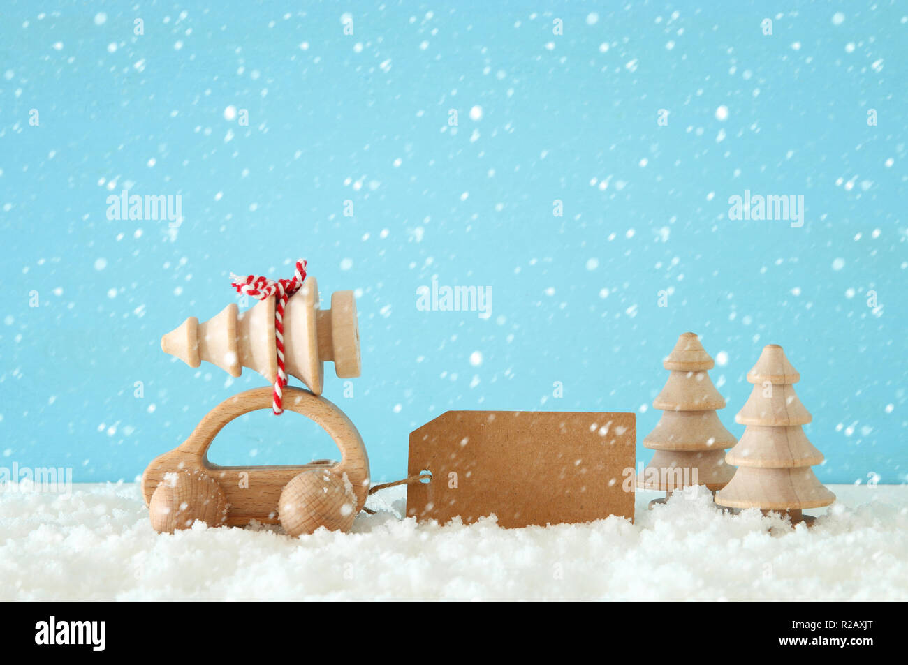 Wooden car carrying a christmas tree in front of pastel background ...
