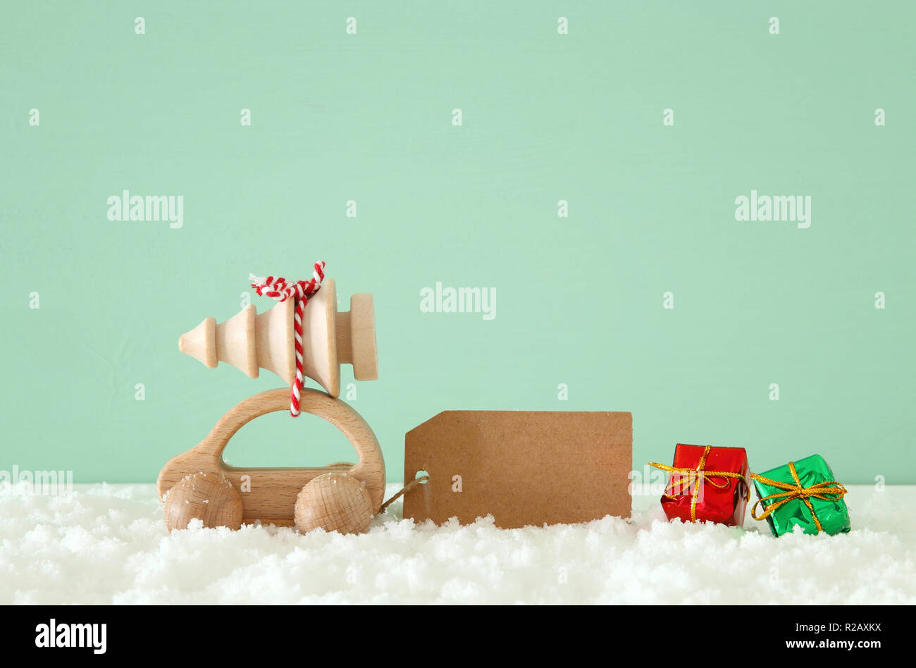 Wooden car carrying a christmas tree in front of pastel background ...