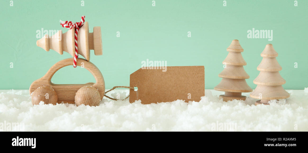 Wooden car carrying a christmas tree in front of pastel background ...