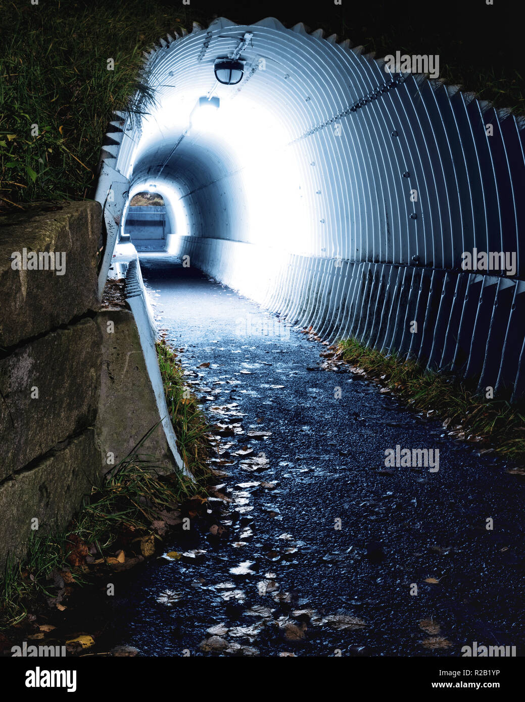 Dark and empty pedestrian underpass made of corrugated galvanised iron ...