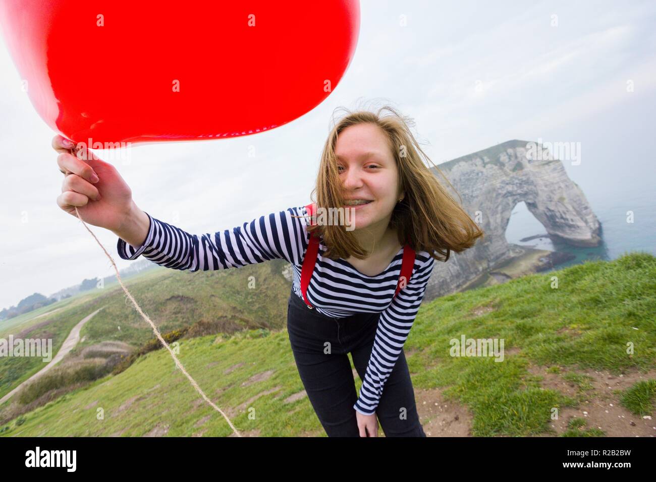 smiling happy girl with a red balloon in the shape of a heart at ...