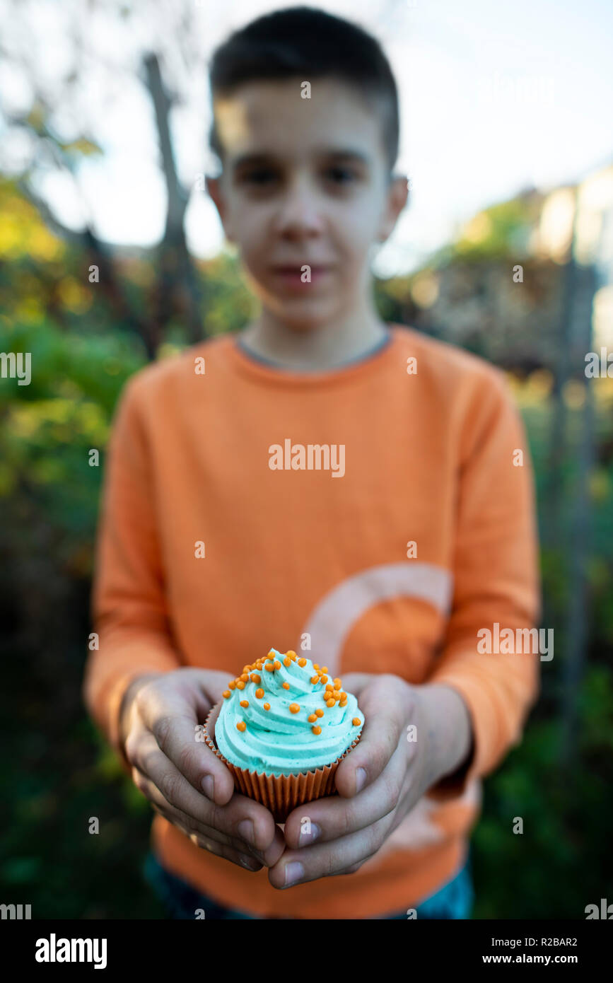 Boy holding blue color muffin. Close up Stock Photo - Alamy