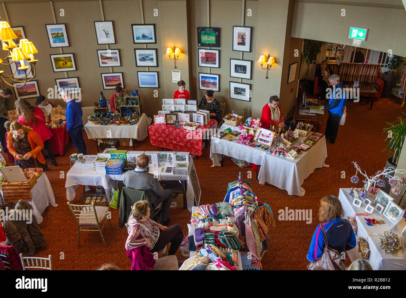 shoppers browsing for gifts and stall holders at an indoor craft market ...